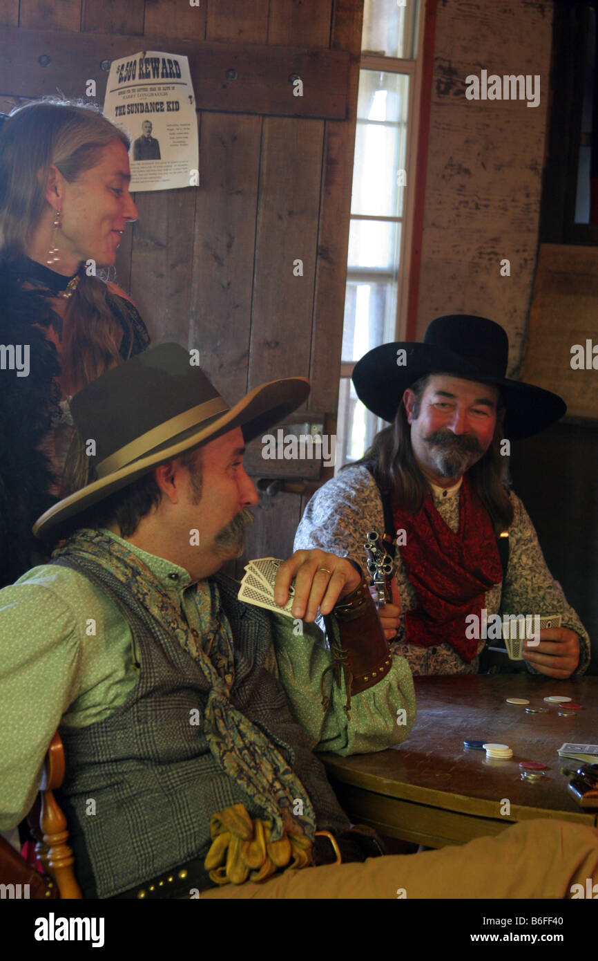 A cowboy pulling a gun and accusing another cowboy playing a card game ...