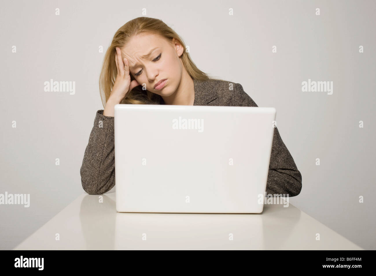 Young long-haired woman sitting frustrated in front of her computer ...