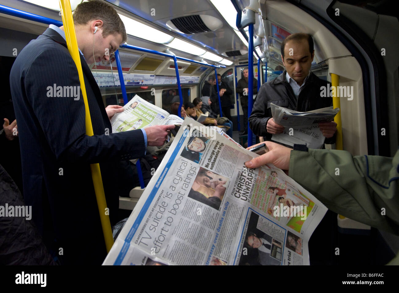 Commuters on underground train reading newspapers London United Kingdom ...