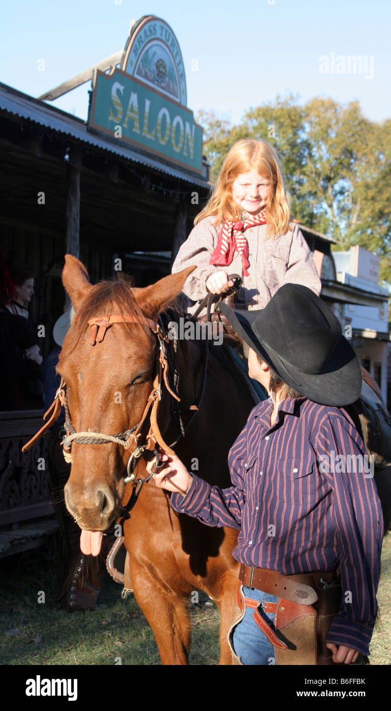 A young cowboy leading a horse with a cowgirl sweetheart riding Stock ...