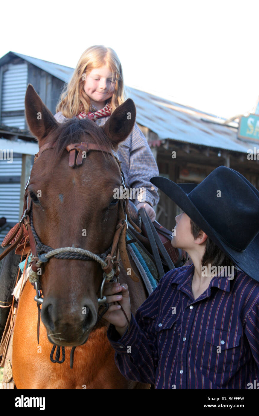 A young cowboy leading a horse with a cowgirl sweetheart riding Stock ...