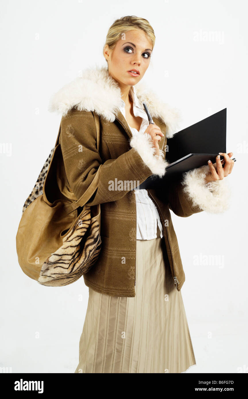 Young woman wearing a winter jacket holding a leather folder open ...