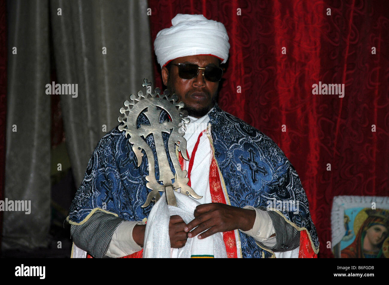 Priest wearing a white turban and cape carrying the Lalibela cross of ...