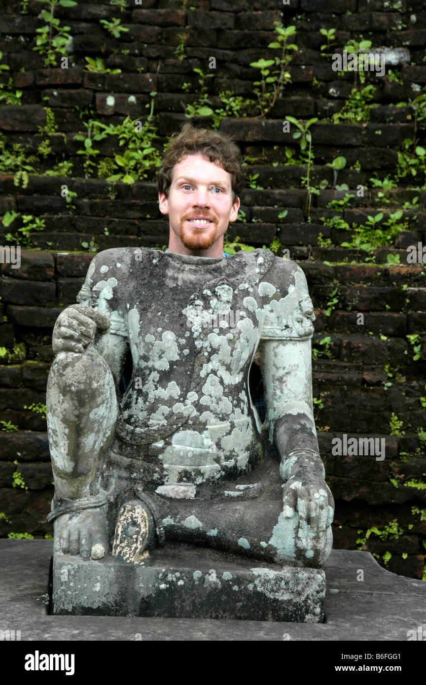 Man standing behind headless statue in the temple of the Cham group B ...