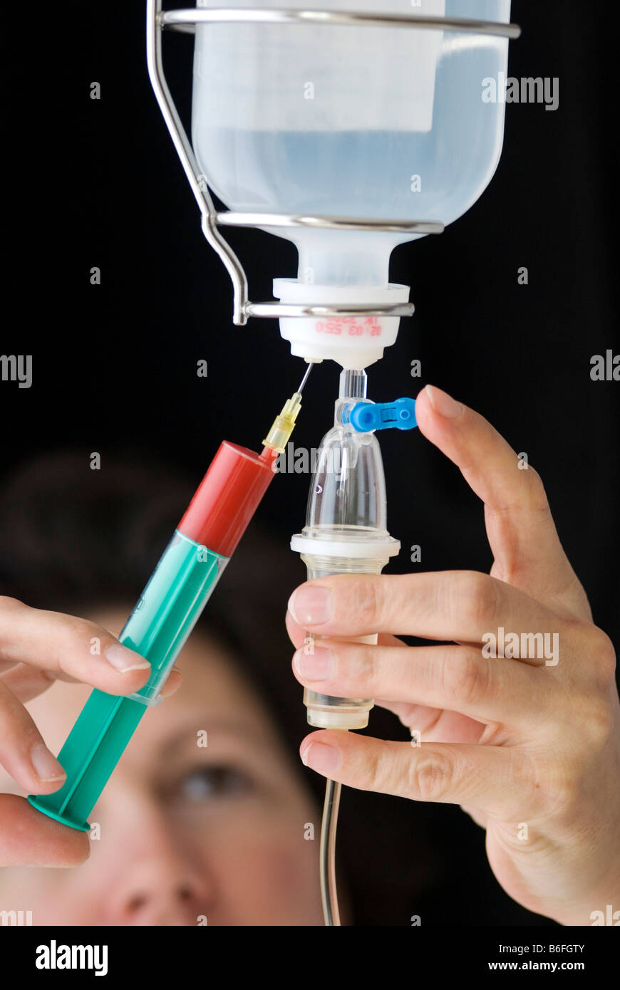 Doctor preparing an infusion by injecting medicine into the infusion ...