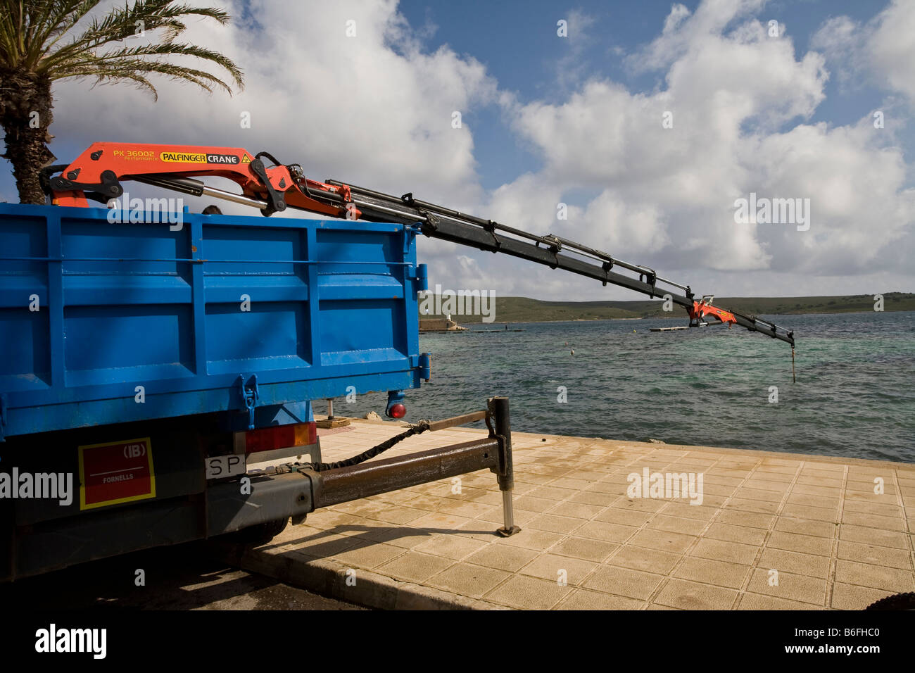 Long reach crane fixed to the rear of a wagon reaching into the sea ...