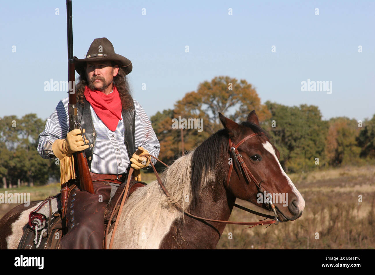 A cowboy on horseback with his rifle Stock Photo - Alamy