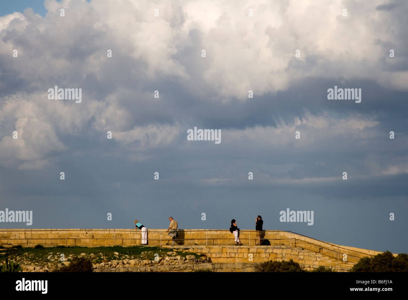 Tourists admire the view from a high point while moody clouds form ...