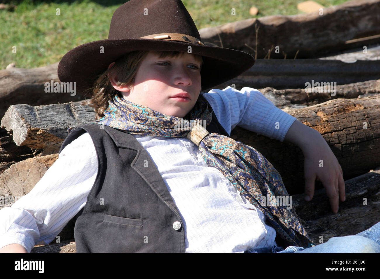 a young boy cowboy resting on a woodpile Stock Photo - Alamy