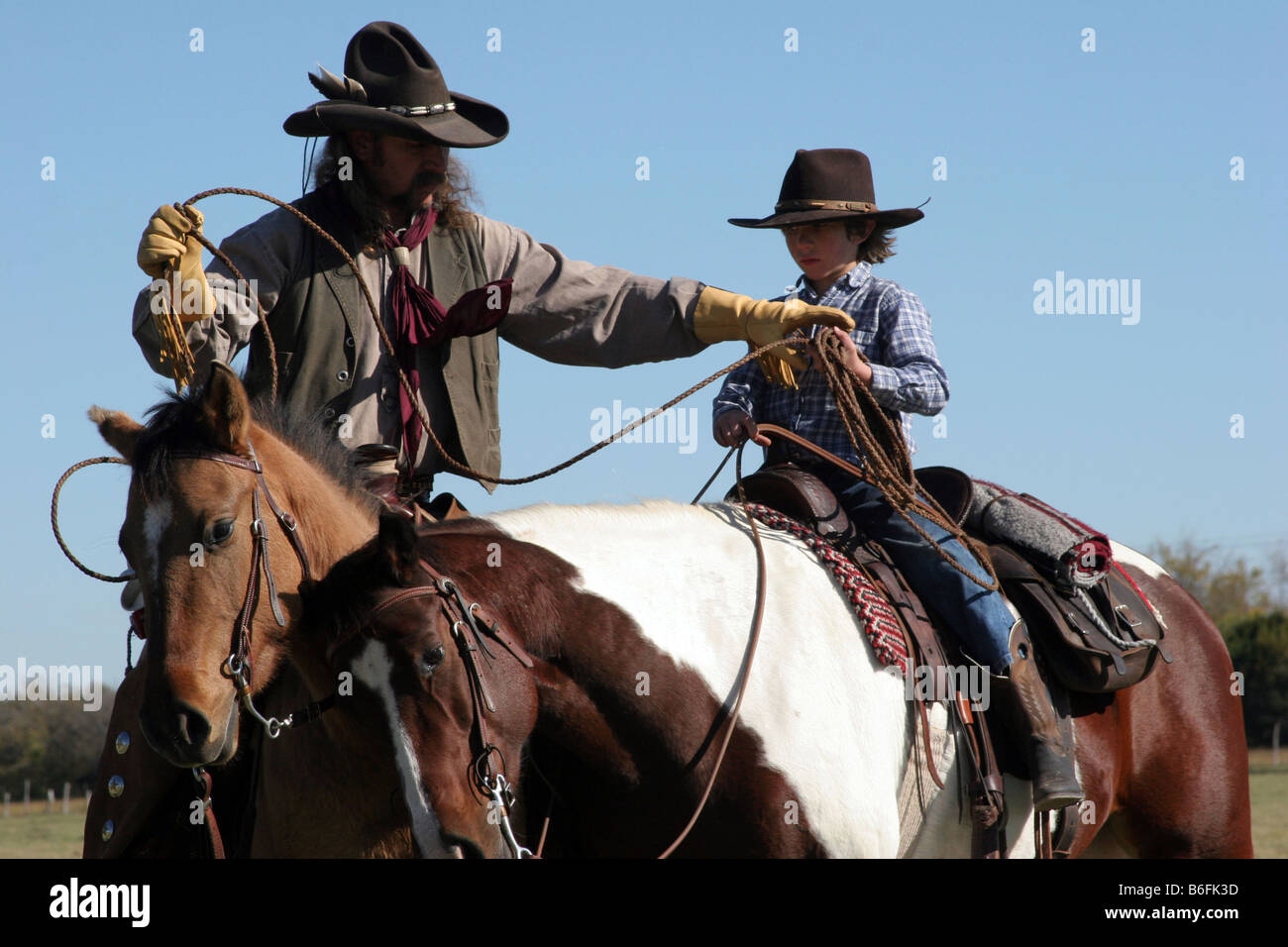A cowboy father showing his son how to rope a cow on the ranch Stock ...