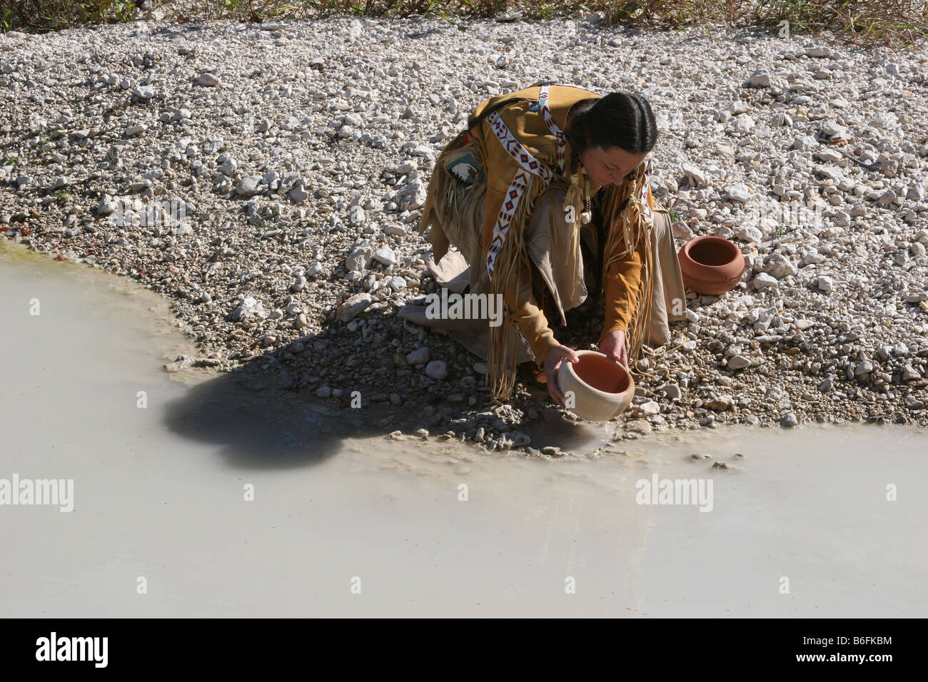 A Native American Indian woman filling pots full of water from the ...