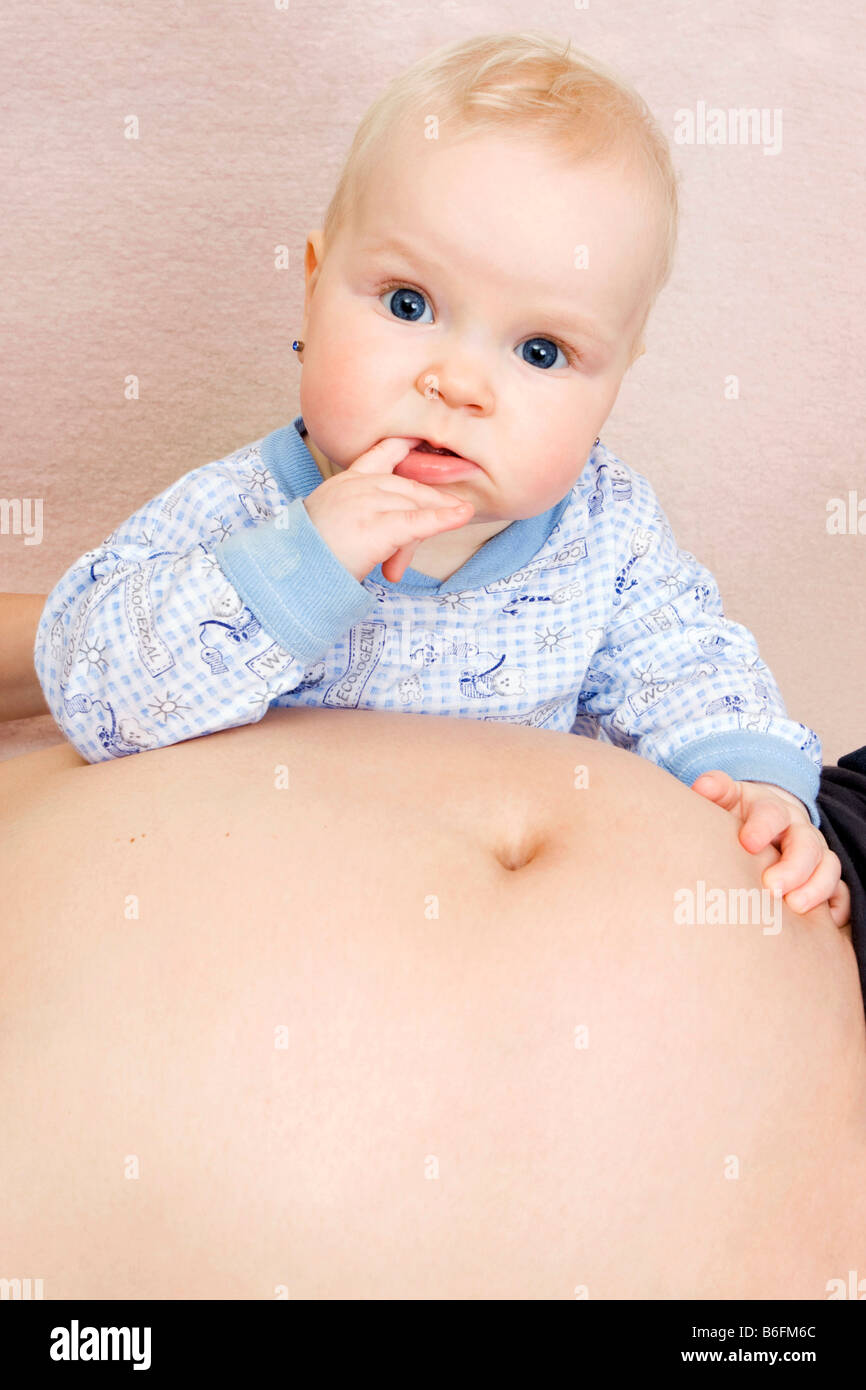 Baby, 7 months, with belly of pregnant mother Stock Photo - Alamy