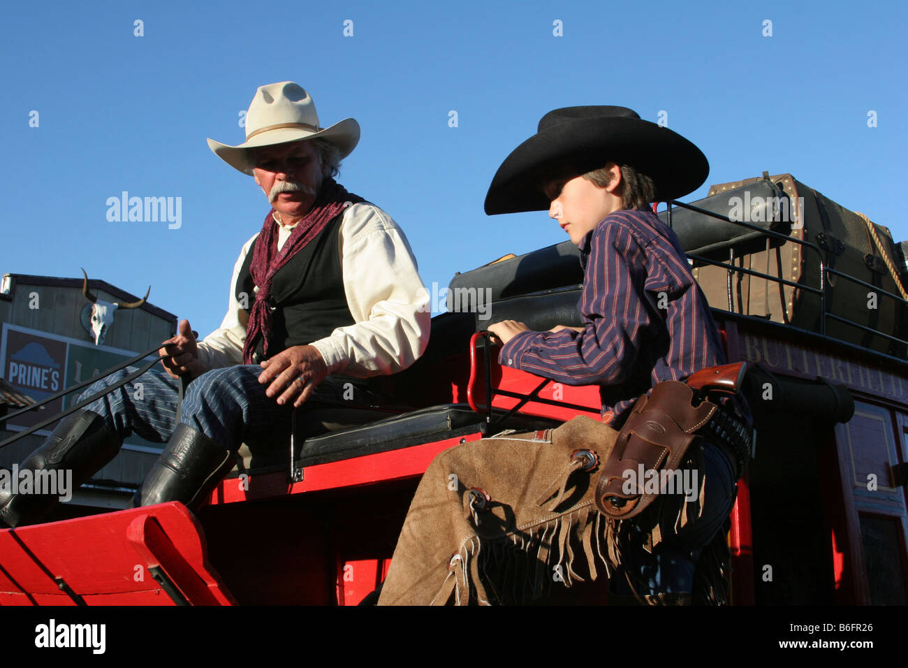 A young cowboy climbing up onto a stage coach drivers seat in an old ...