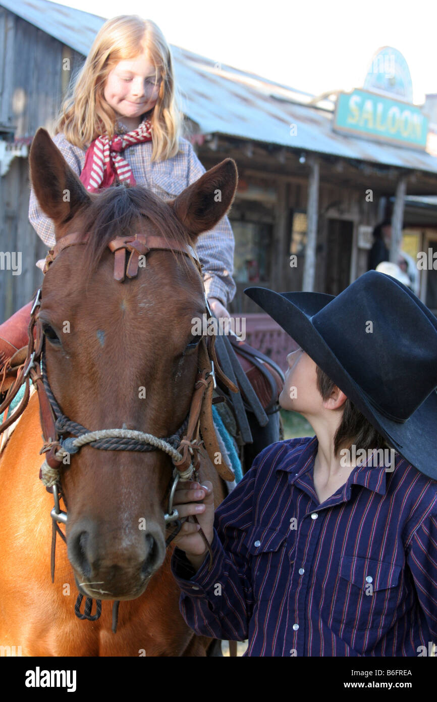A young cowboy leading a horse of a cowgirl riding above Stock Photo ...