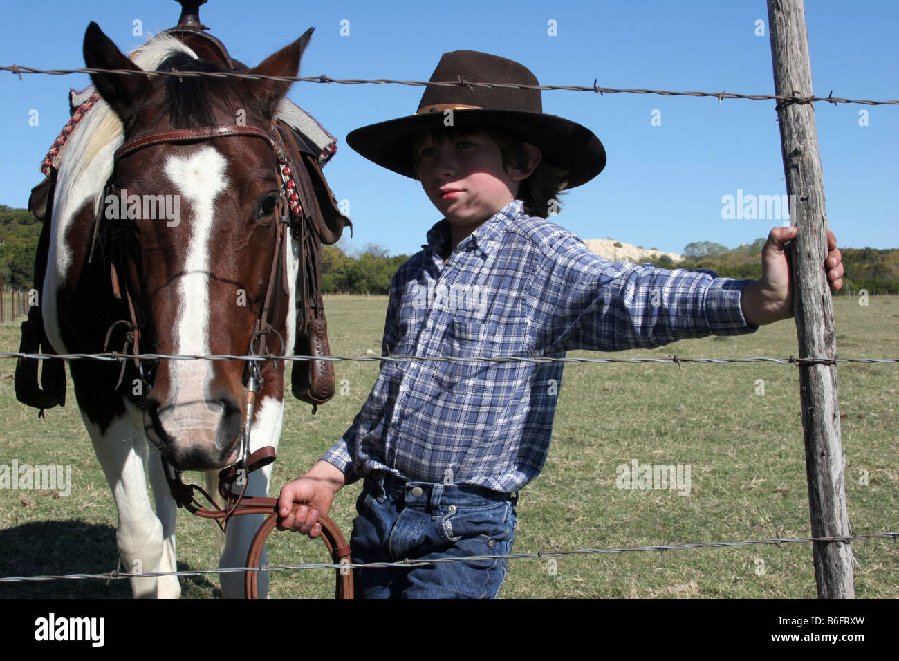 A young cowboy with his horse taking a break from working the ranch ...
