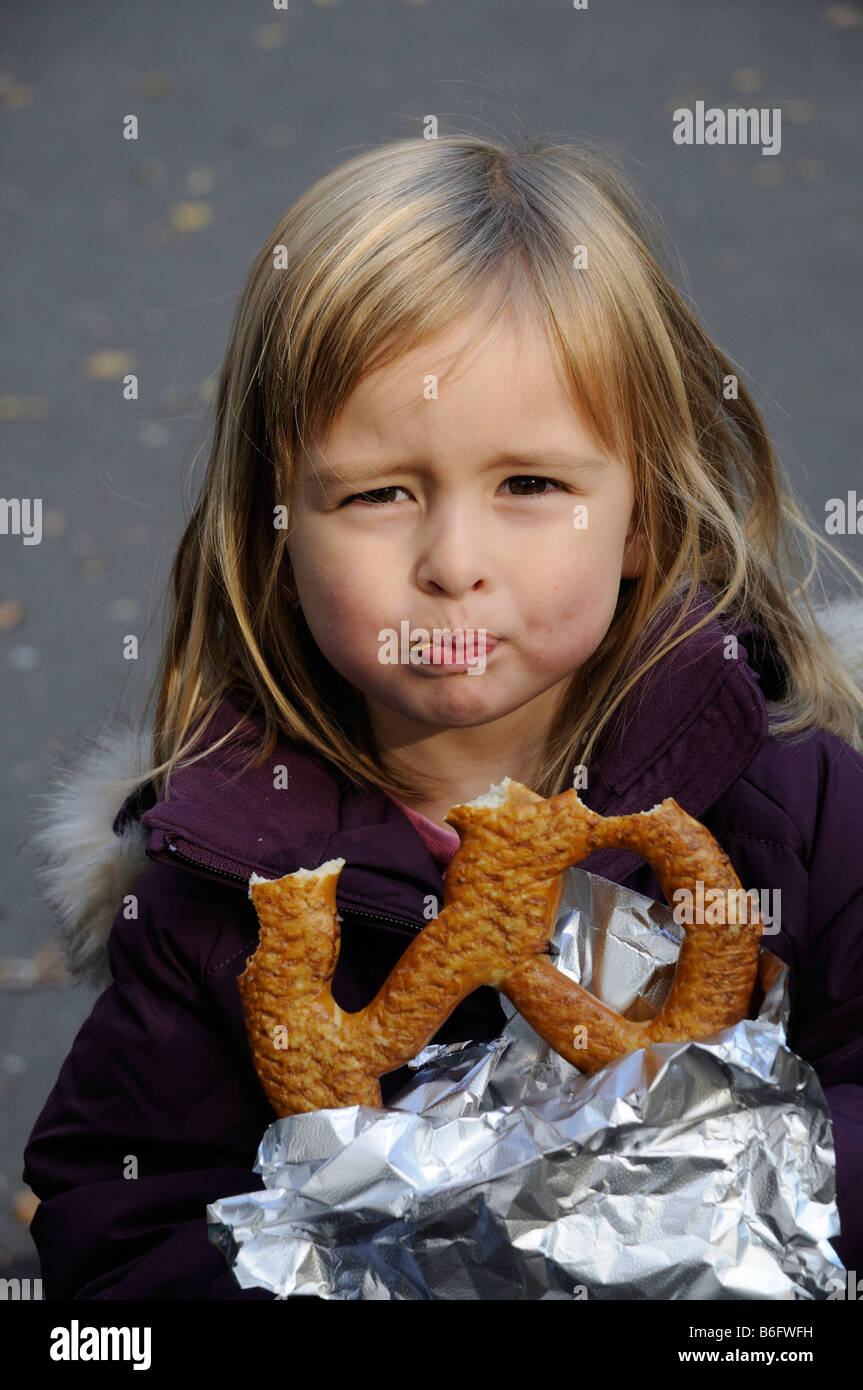 Little girl enjoys chewing on a pretzel biscuit Stock Photo - Alamy