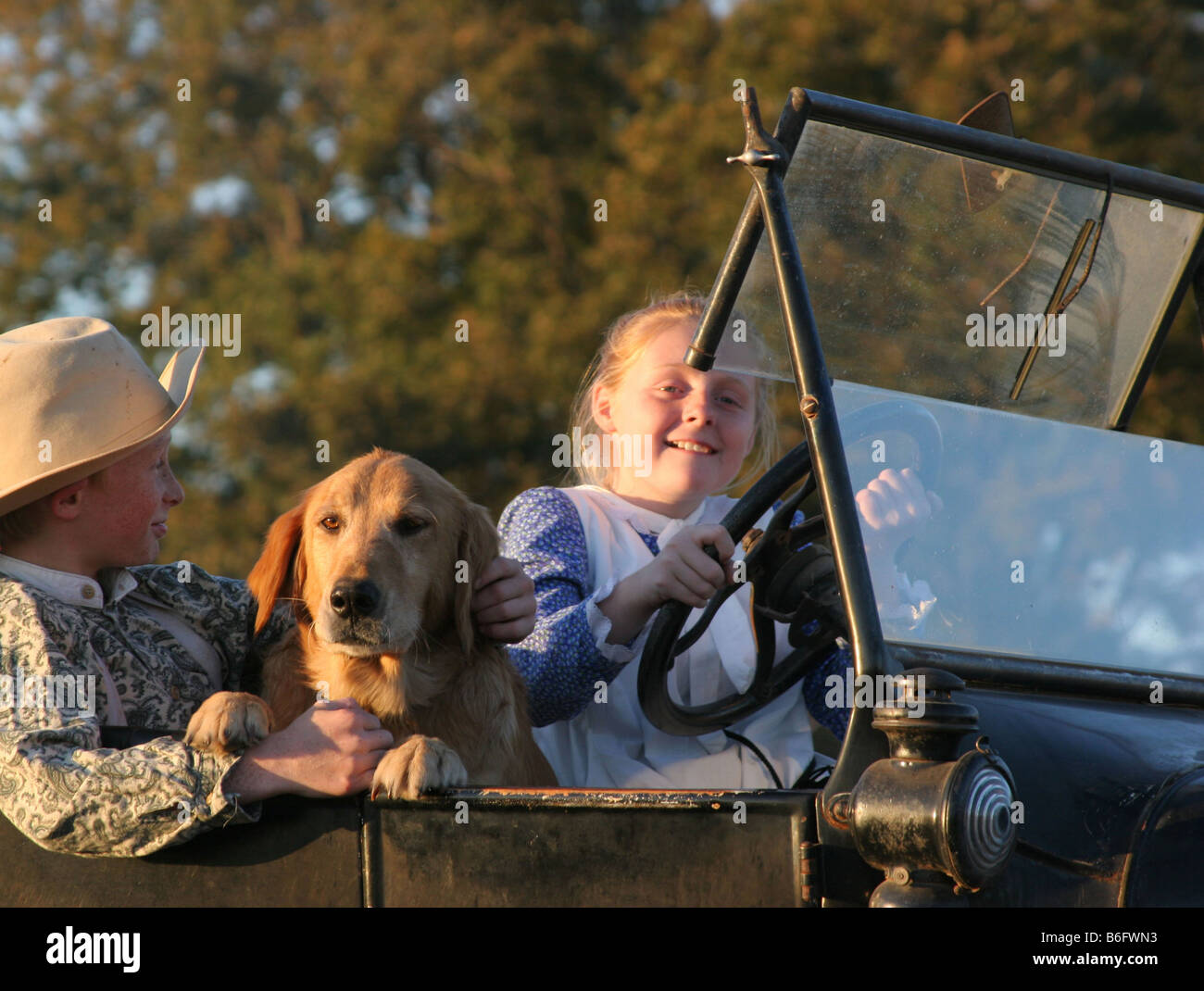 Two kids and a dog riding in an old car Stock Photo - Alamy