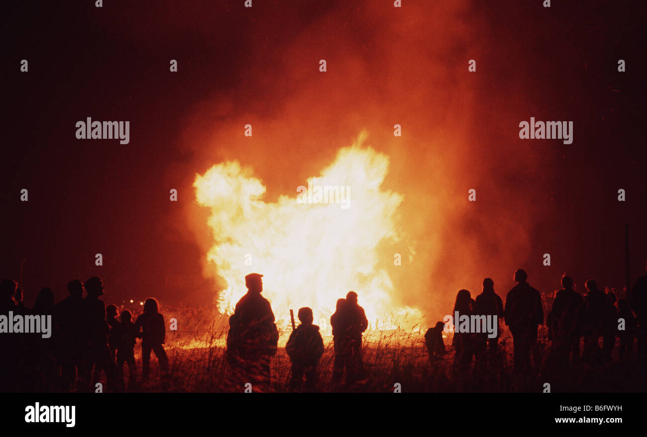 People watching a bonfire blaze silhouetted against the flames Stock ...