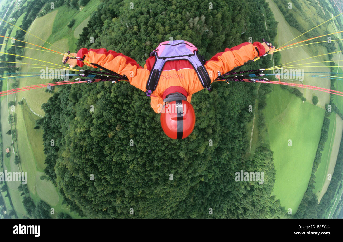 Paraglider flying in 500 ft above ground relaxed in upwind over woody ...