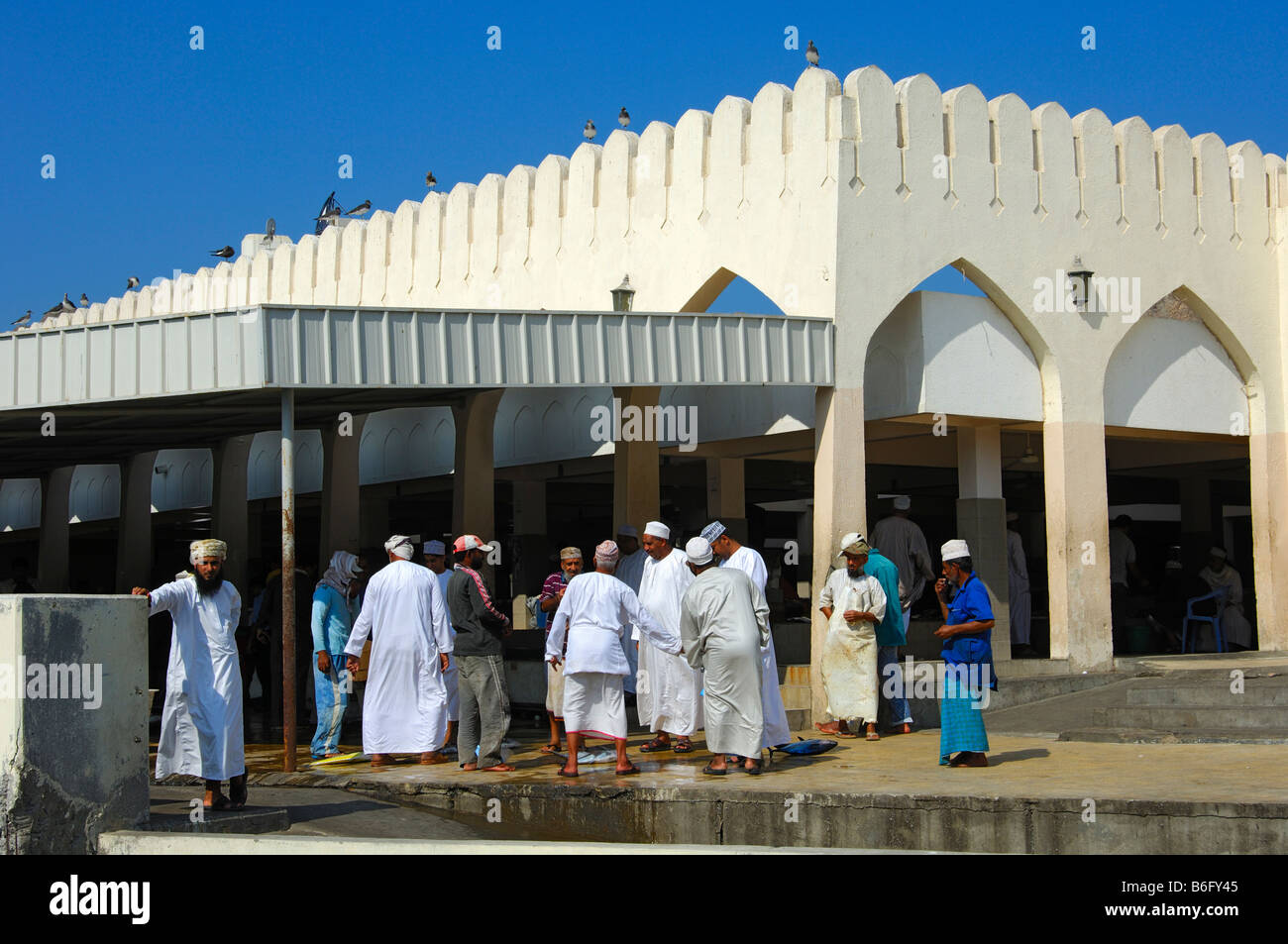 Omani men wearing the national dress chatting in front of the Mutrah ...