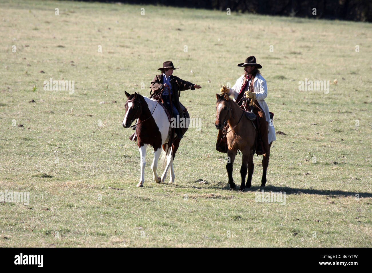 A cowboy and his son out on the range to round up cattle and the son is ...