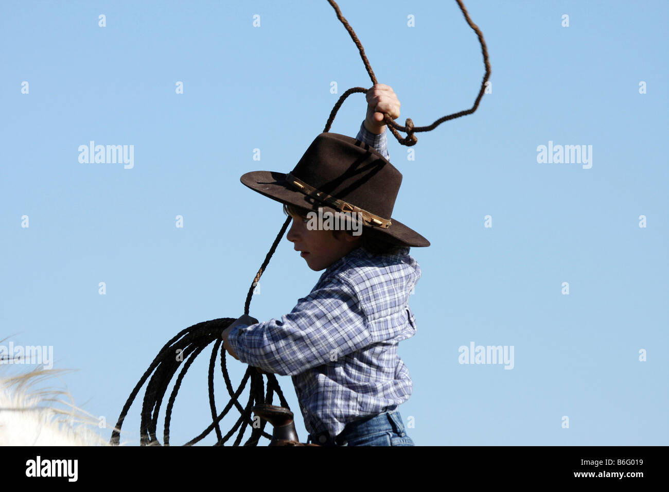 A young cowboy throwing a rope from horseback on a ranch in Texas Stock ...