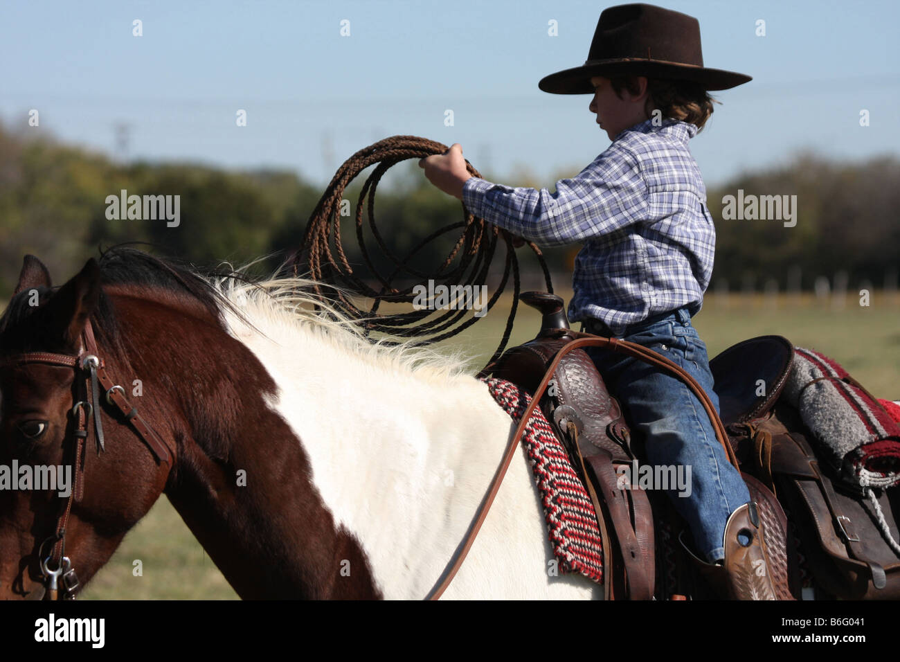A young cowboy getting the rope ready to throw from horseback Stock ...