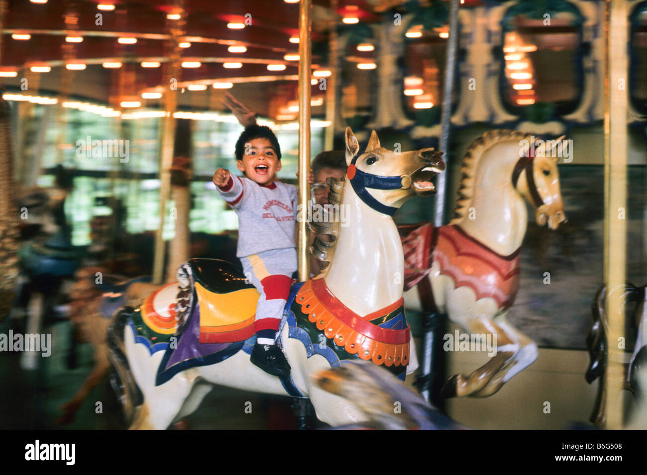 Toddler waves and laughs as he rides merry-go-round carousel at ...