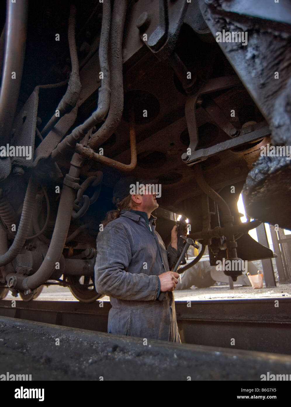 Engineer checking the underside of a steam locomotive before its ...
