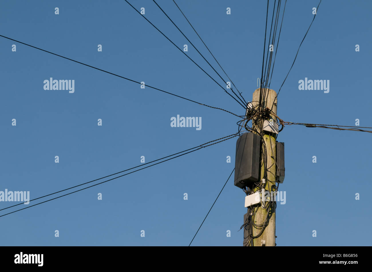 telephone lines radiating out from the top of a telegraph pole against ...