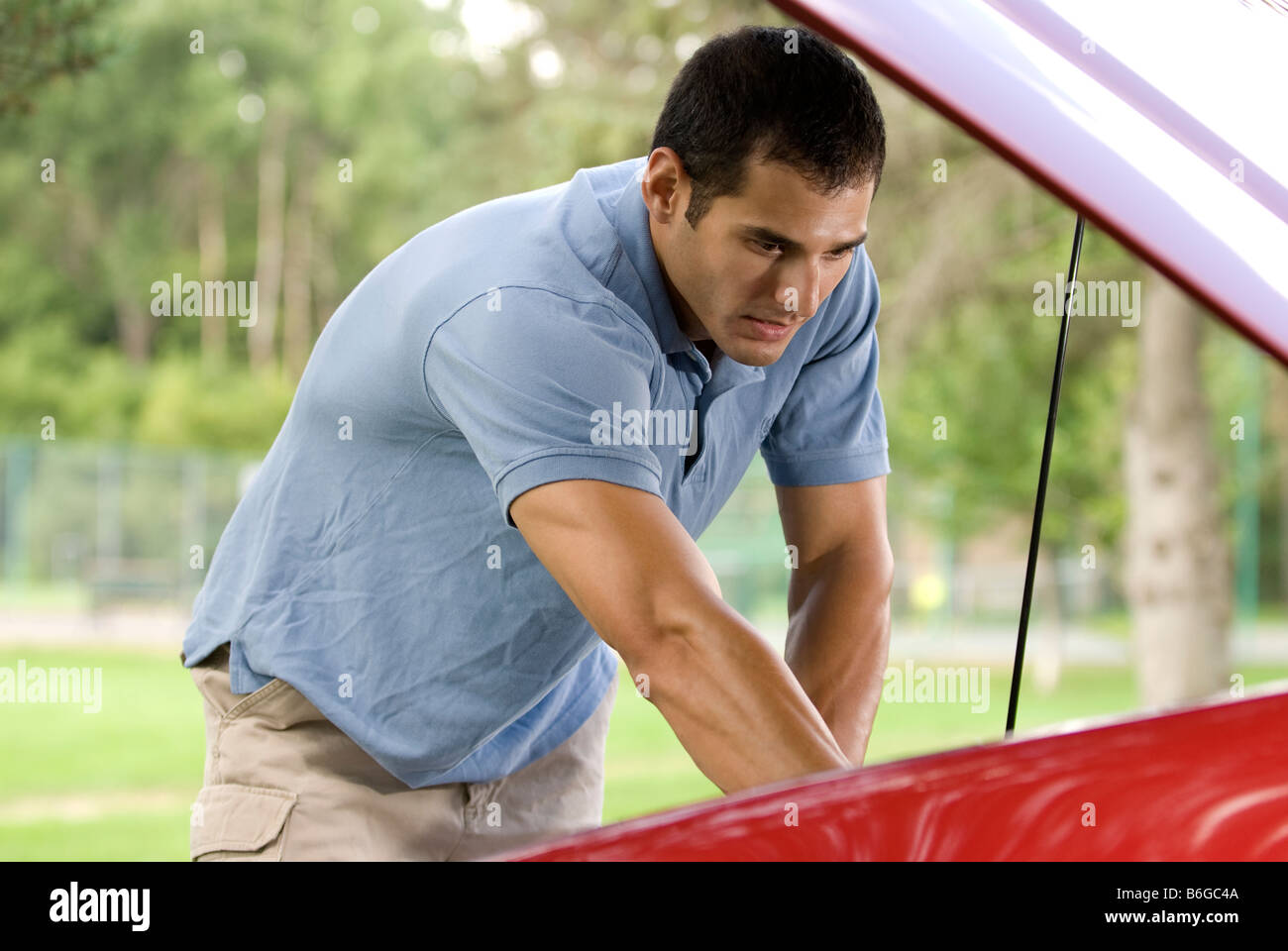 Man reaching into car engine compartment trying to fix it Stock Photo ...