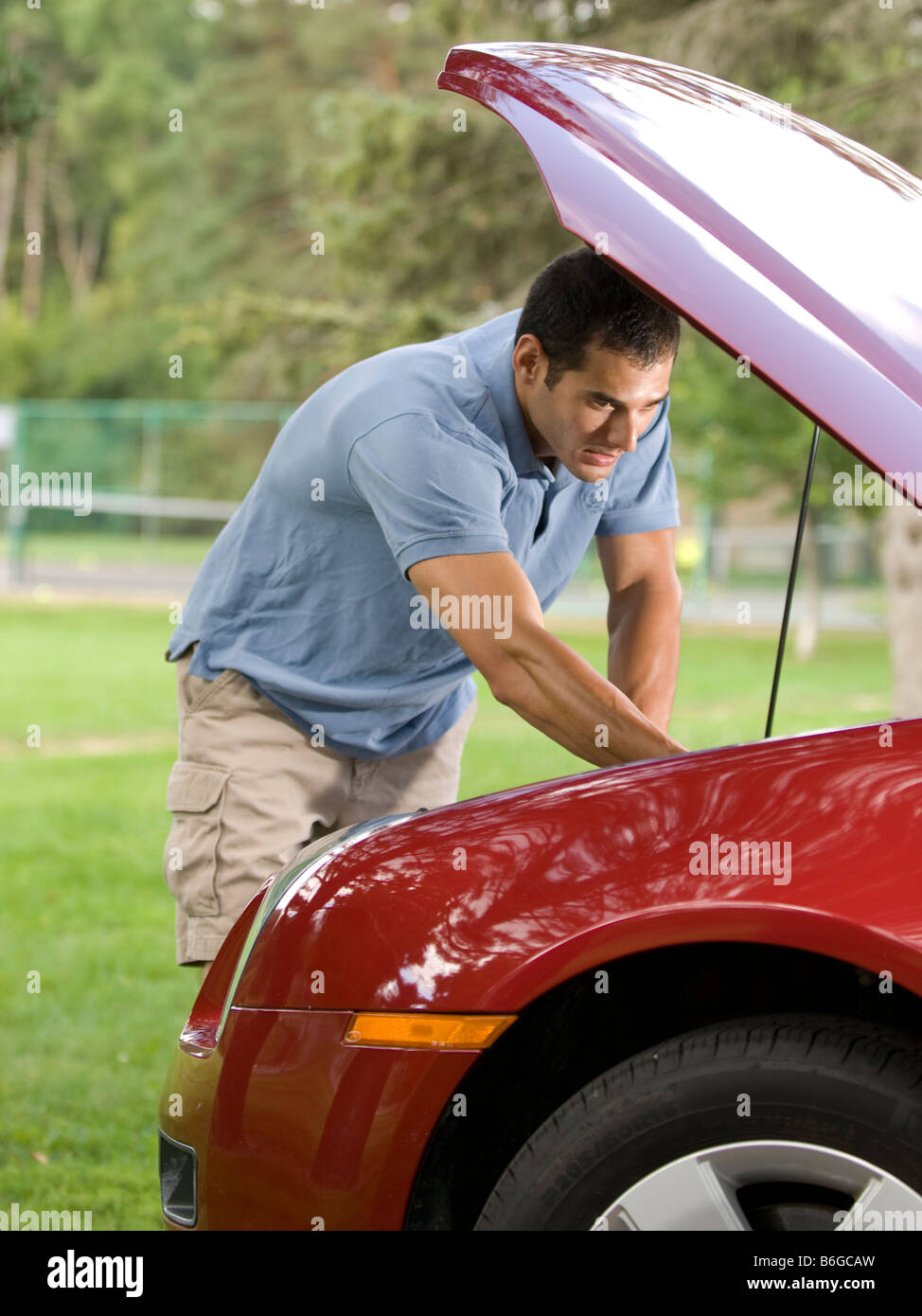 Man reaching into car engine compartment trying to fix it Stock Photo ...