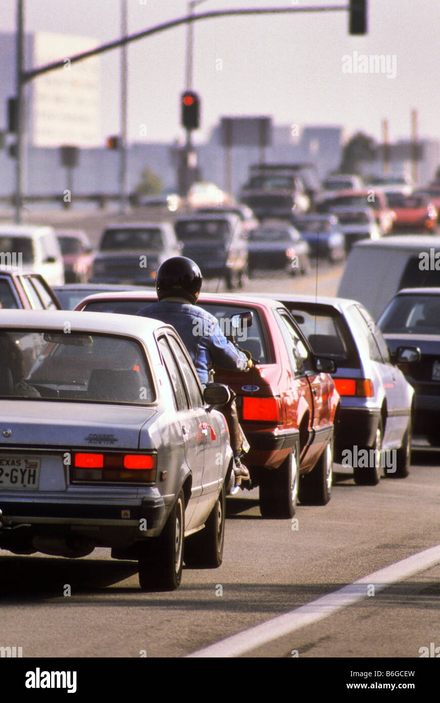 Motorcycle rides between cars on highway Stock Photo - Alamy