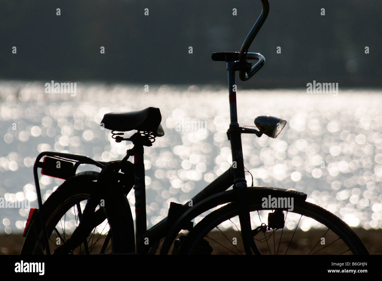 Old dutch traditional bicycle silhouette standing by lake water ...