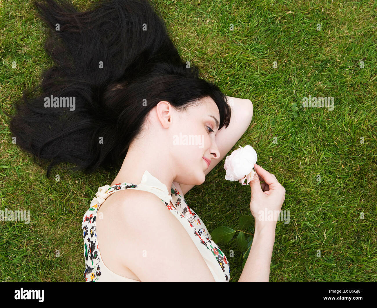 Woman laying on grass, smelling rose Stock Photo - Alamy