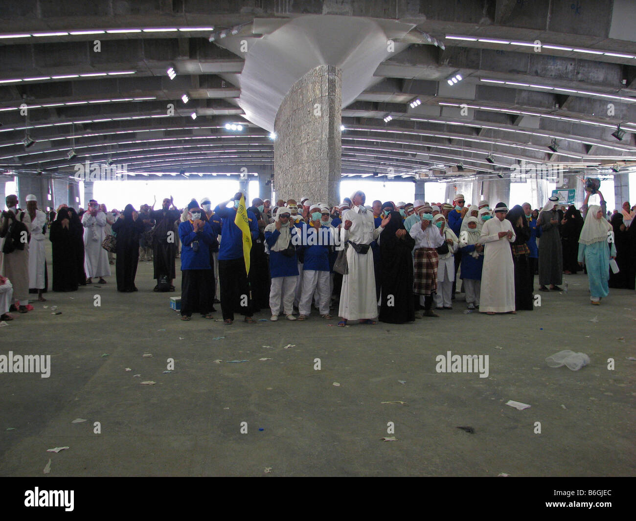 Pilgrims praying next to one of the three pillars that symbolices the ...