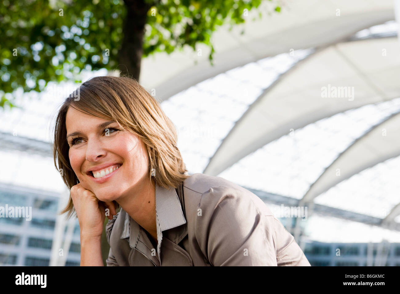 Woman sitting outdoors smiling Stock Photo - Alamy