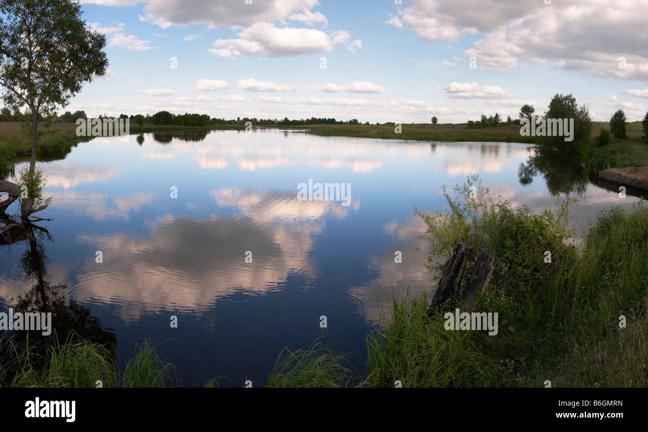 Summer rushy lake panorama view with clouds reflections. Four shots ...
