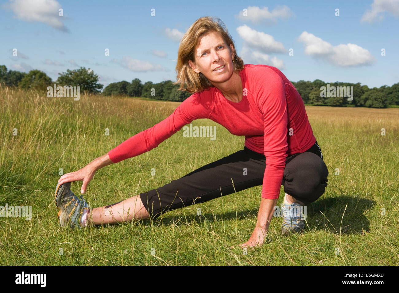 Woman stretching leg in field Stock Photo - Alamy