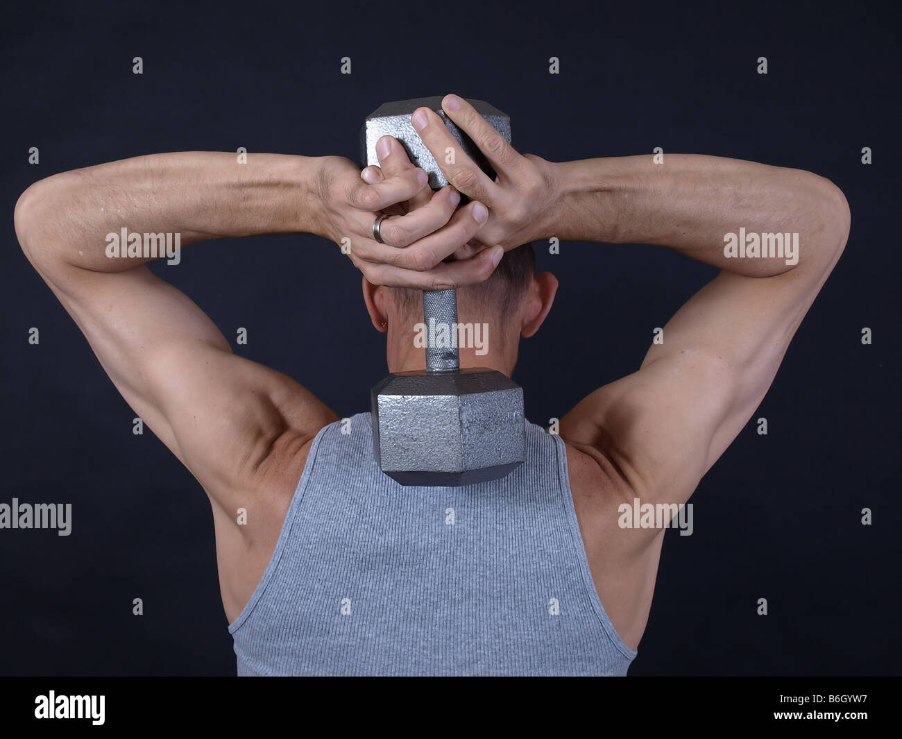 A man holds a weight behind his head working his arms and shoulders ...