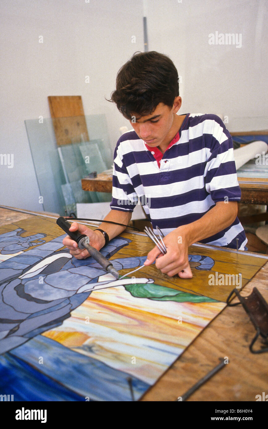 Teen boy creates stained glass window with glass and solder Stock Photo ...
