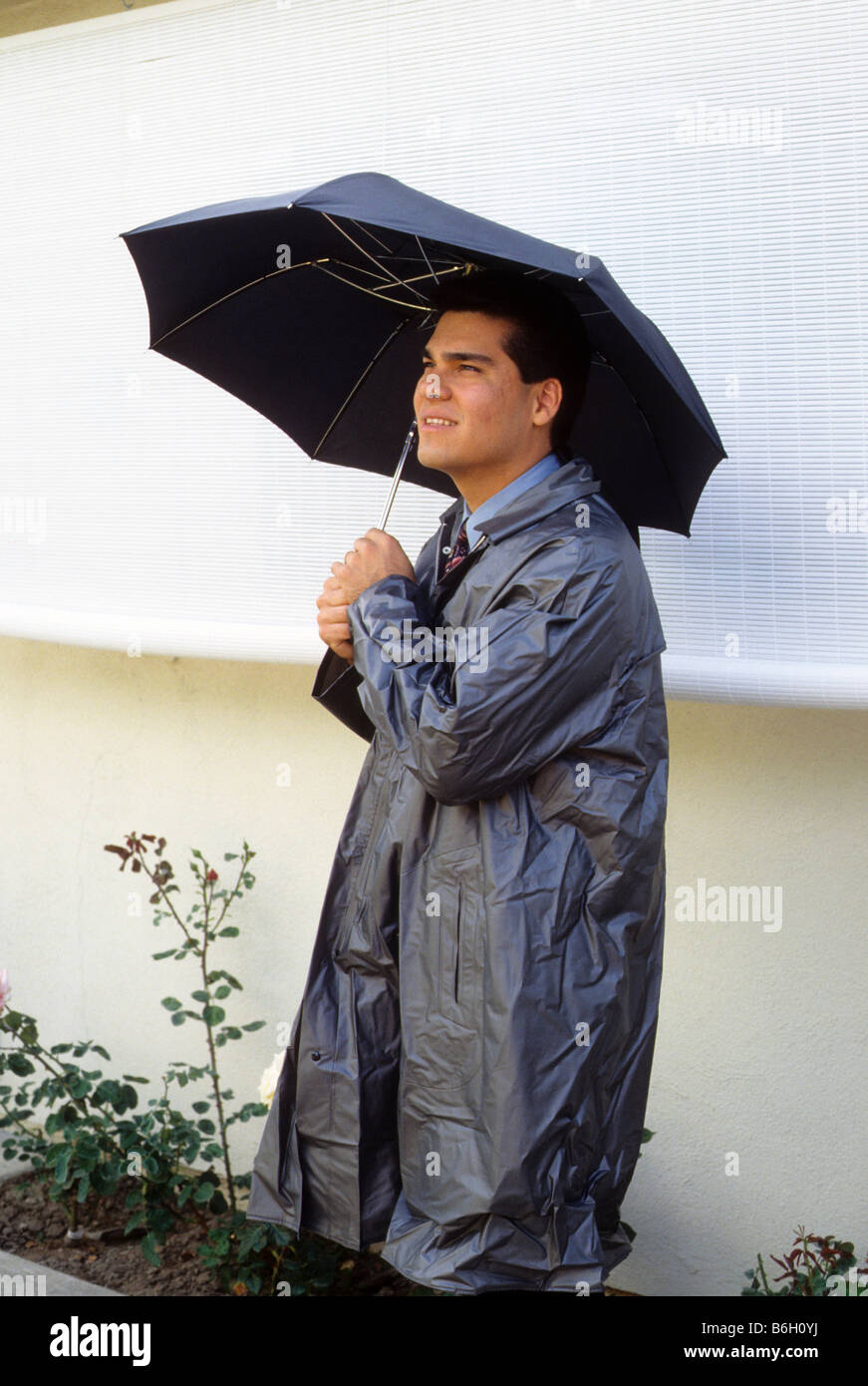 Hispanic man in raincoat protects himself from rain with umbrella Stock ...