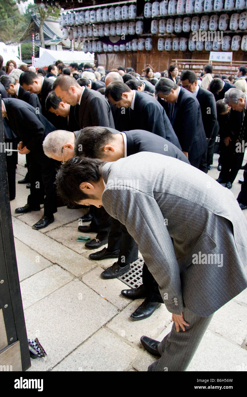 Group of Japanese business men in suits, salarymen, bowing, praying for ...