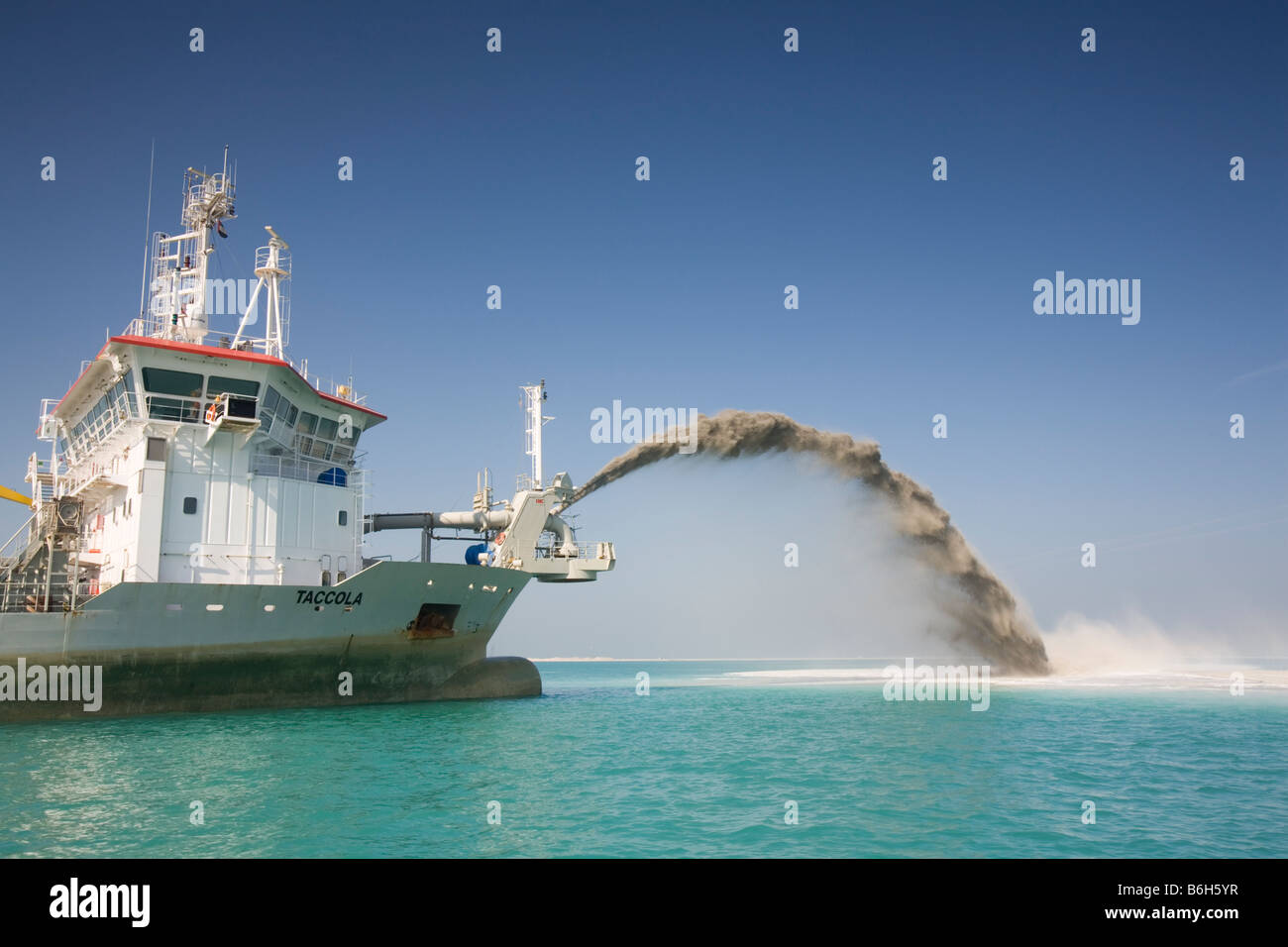 Trailing suction hopper dredger rainbowing sand to form new land on one ...