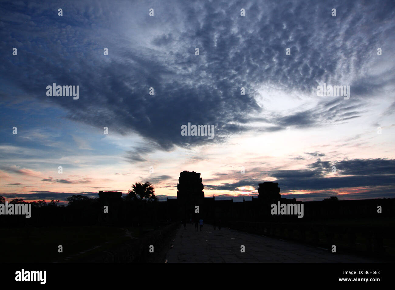 Black shape of Angkor Wat temple taken after sunset with a reddish sky ...