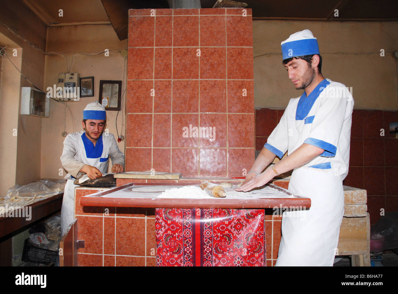 A baker making traditional unleavened bread in a tandoori oven in ...