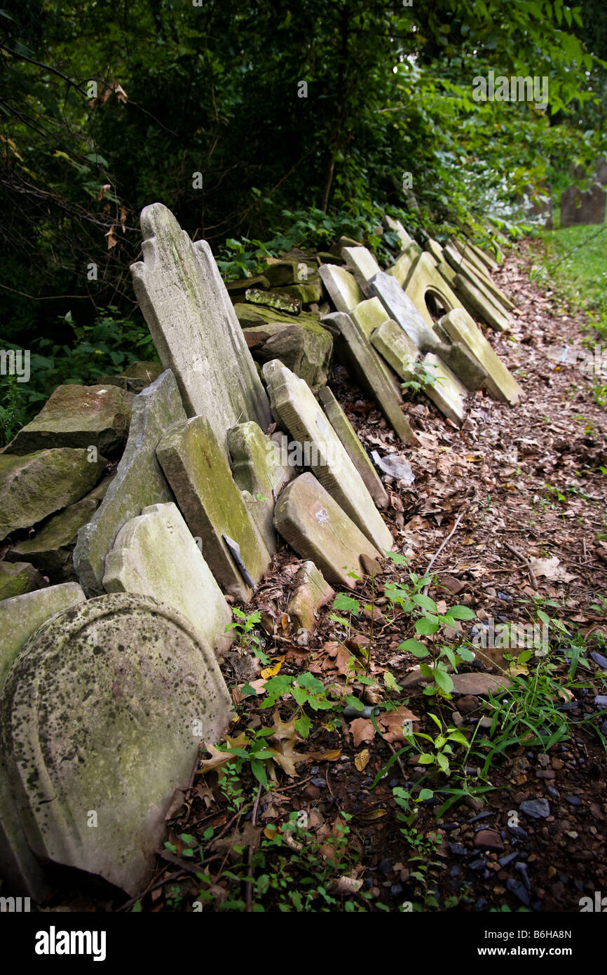 Old discarded , worn and broken tombstones stacked against a stone wall ...