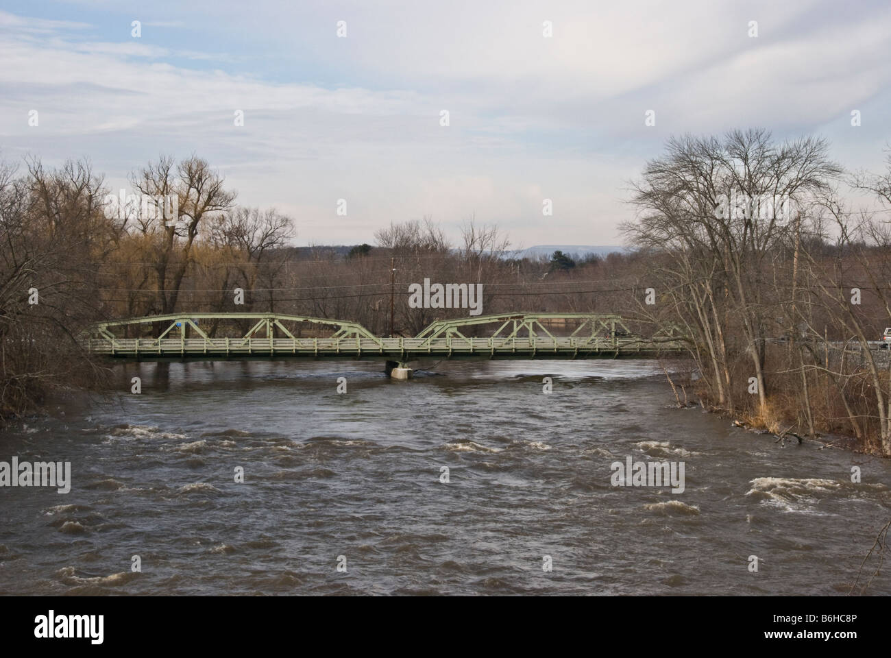 old green-painted, rusted iron-truss bridge spans the Wallkill River at ...