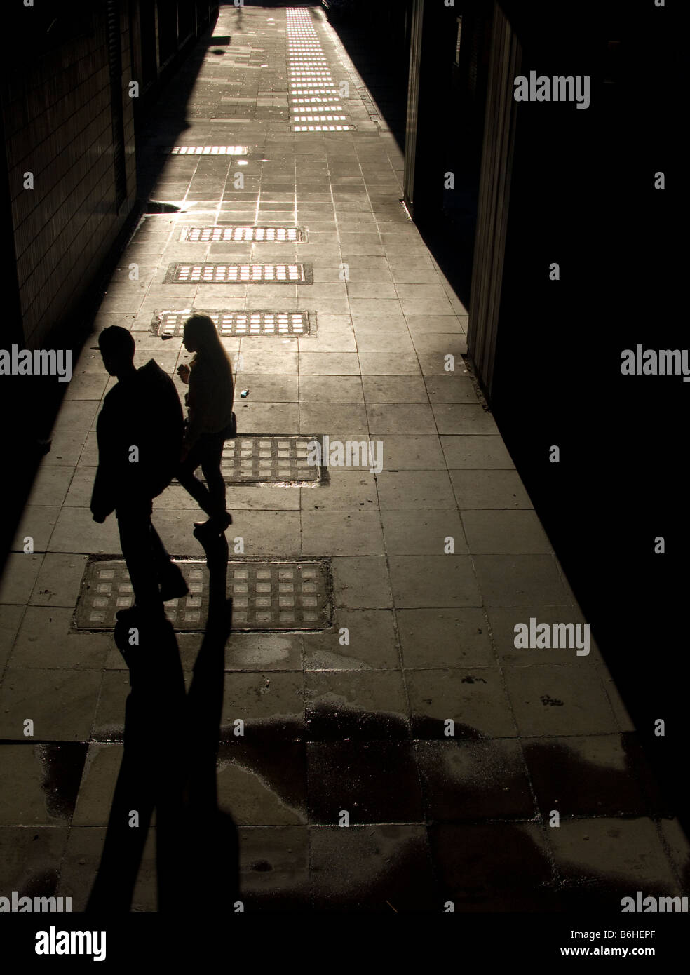 Two silhouetted youths walk across sunlight alleyway Stock Photo - Alamy