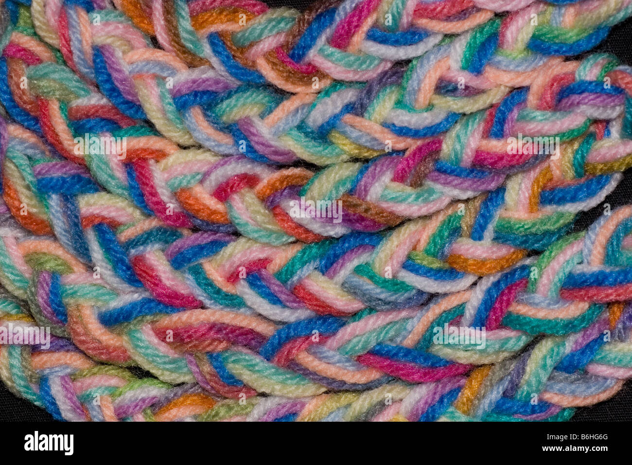 Braided multi colored strands of wool laid in a curved pattern side by ...